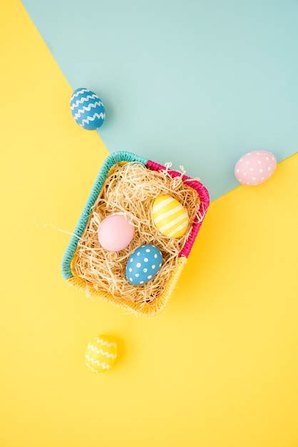 Ovos de páscoa coloridos na pequena cesta na mesa Foto Grátis