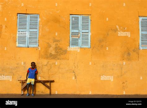 A Boy Is Posing In Front Of A Wall Of A Typical Colonial House Painted