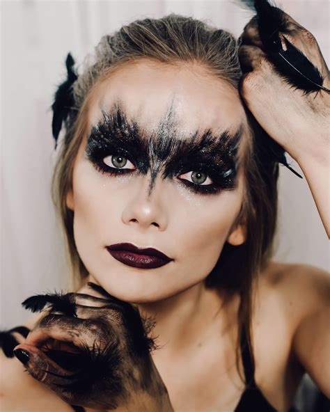 A Woman With Black Makeup And Feathers On Her Head Is Holding A Monkey