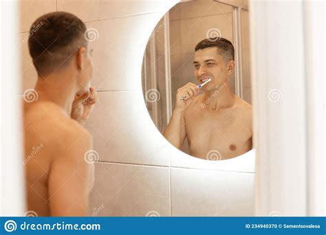 Reflection In The Mirror Of The Naked Attractive Guy Doing Hygiene