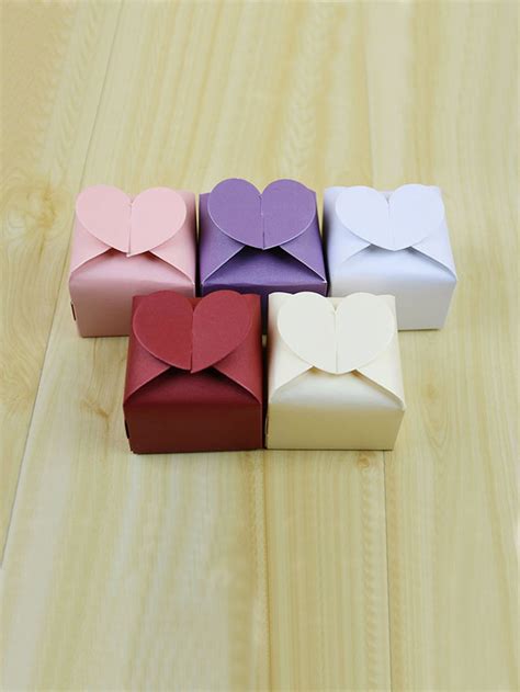 Four Different Colored Boxes With Hearts On Them Sitting On A Wooden