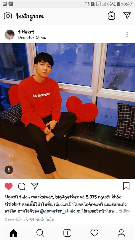 A Man Sitting On Top Of A Black Couch Next To A Red Heart Shaped Pillow