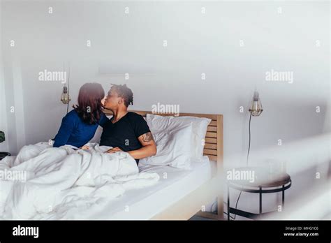 Romantic Couple Kissing In Bed Interracial Man And Woman Sitting On