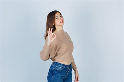 Retrato de dama maravillosa mostrando gesto ok en suéter jeans y