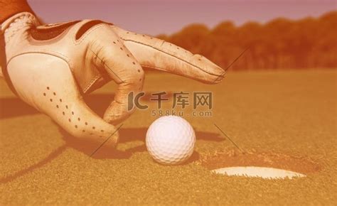 S在球场上用手把高尔夫球打进洞里的特写男子S将高尔夫球打入球洞高清摄影大图 千库网