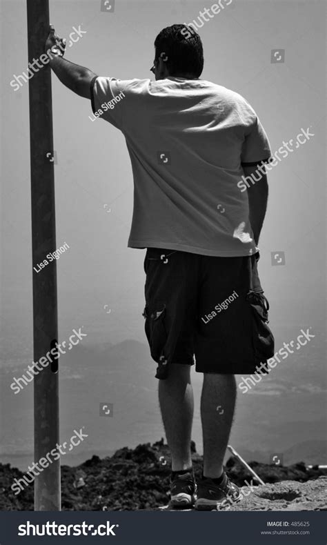 A Man Leaning Against A Pole Looking At Mountains Stock Photo