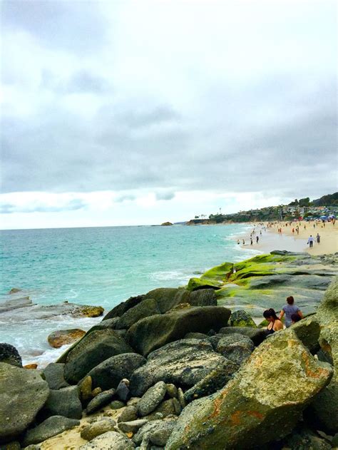 Two People Sitting On Rocks Near The Ocean