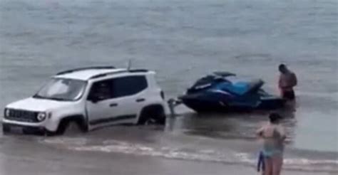 Carro atola na beira do mar ao tentar retirar moto aquática em