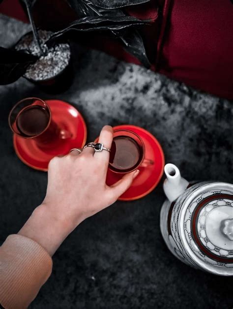A Woman Is Holding Two Red Cups And Saucers