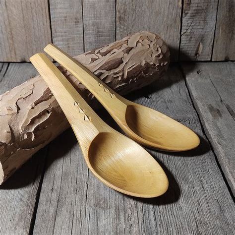 Two Wooden Spoons Sitting On Top Of A Piece Of Wood