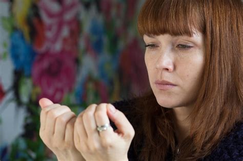 Retrato de la mujer de mediana edad mirando sus uñas disgustada Foto