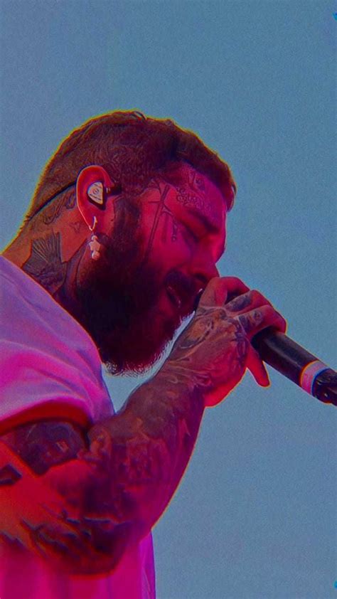 A Man With Tattoos And Piercings On His Face Holding A Microphone In