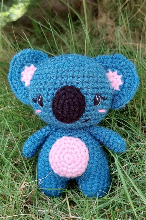 A Crocheted Blue Teddy Bear Sitting In The Grass With It S Eyes Closed