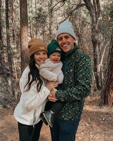 A Man And Woman Holding A Baby In The Woods