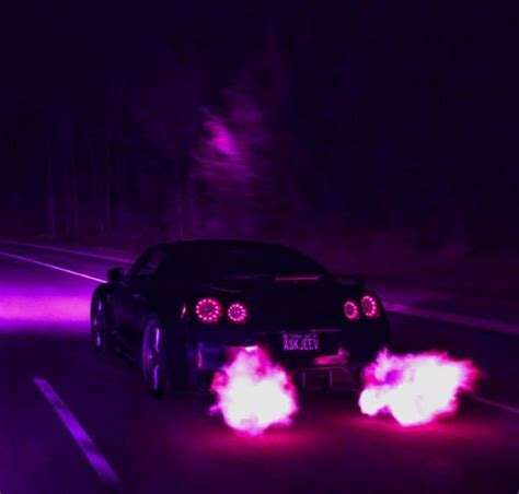 A Car Driving Down The Road With Purple Lights On It S Headlamps