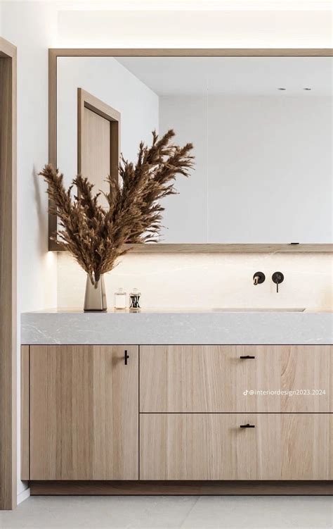 A Bathroom With A Large Mirror Above The Sink And Wooden Cabinetry On