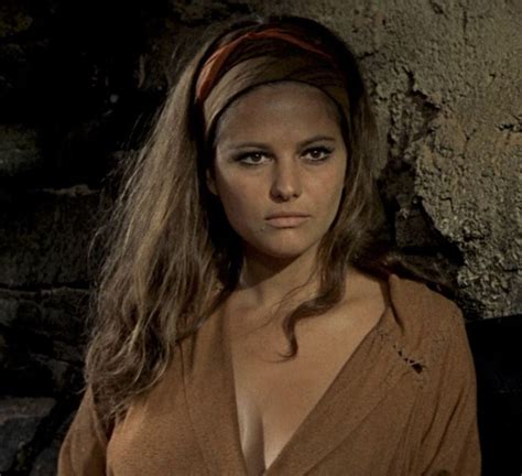 A Woman With Long Hair Standing In Front Of A Stone Wall And Looking At
