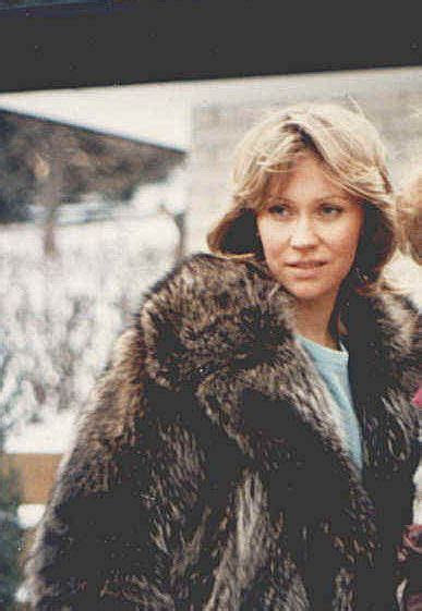 Two Women Standing Next To Each Other In Front Of Snow Covered Trees