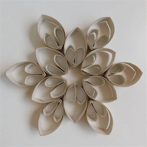 A White Flower Made Out Of Paper Sitting On Top Of A Table Next To A Wall
