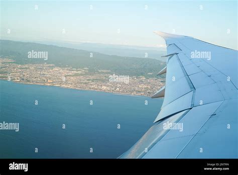 Wing Of An Airplane Flying Above City And Sea Stock Photo Alamy