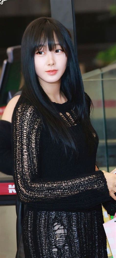 A Woman With Long Black Hair And Bangs Standing In Front Of A Glass