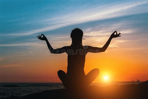 La Silueta De La Mujer Joven De La Yoga Hace La Meditación En La Playa