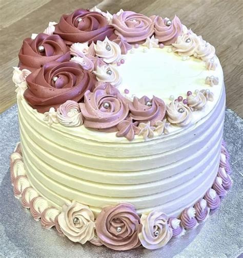 A Multi Layer Cake With White Frosting And Purple Icing Flowers On Top