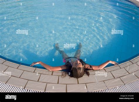 Teenage Girl Relaxing At Edge Of Swimming Pool Stock Photo Alamy
