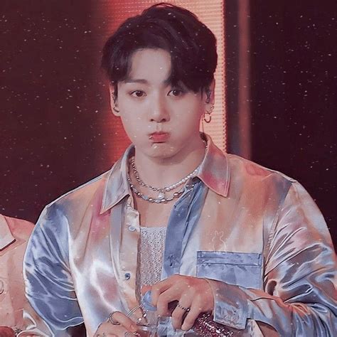 The Man Is Wearing A Shiny Shirt And Holding A Glass In His Hand While
