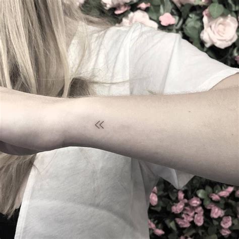 A Woman S Arm With A Small Arrow Tattoo On The Left Side Of Her Arm