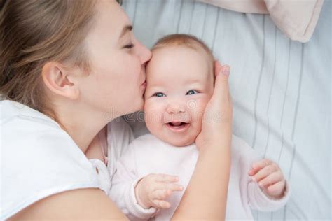 Madre Besando A Su Bebé En Cama La Madre Feliz Besa A Un Bebé En La Cama Bella Sonriente