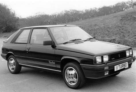 A Black And White Photo Of A Car Parked In A Parking Lot Next To A Hill