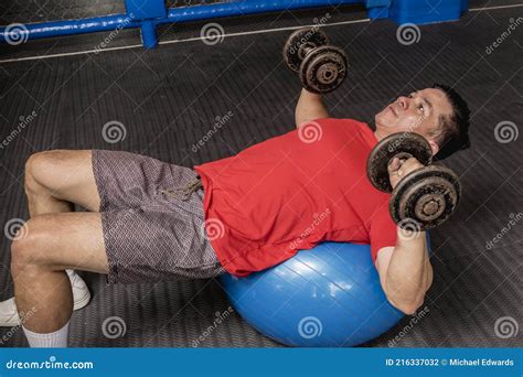 A Fit And Athletic Asian Guy Does Swiss Ball Dumbbell Chest Press Working Out At The Gym Stock