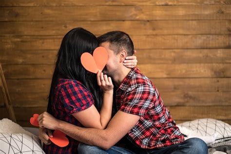 Casal Romântico Sentado Em Um Sofá Em Um Abraço Amoroso Beijando Enquanto Seguram Um Coração De