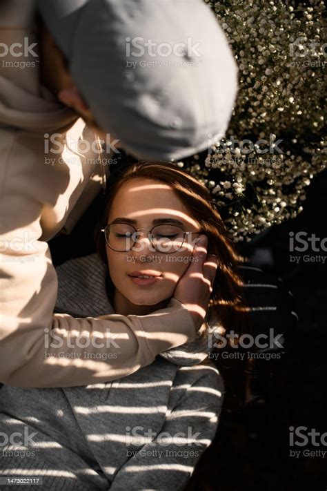 Top View Of Woman Lying With Her Eyes Closed And Young Man Bending Over Her And Hugs