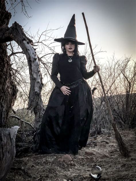 A Woman Dressed As A Witch Holding A Broom And Wearing A Black Dress
