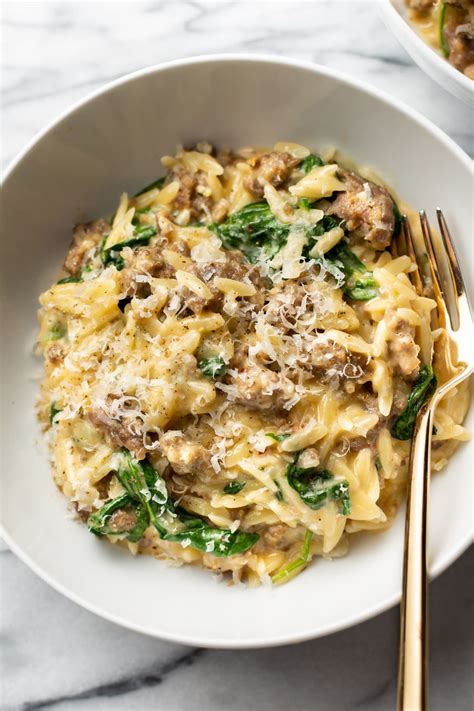 A White Bowl Filled With Pasta And Meat On Top Of A Marble Table Next