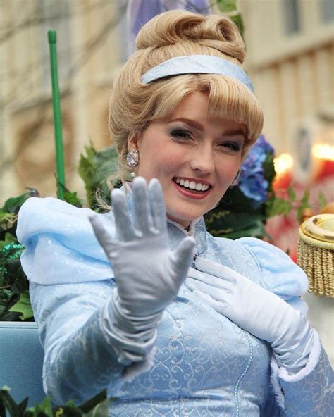 A Woman Dressed In Blue Waving At The Camera With Her Hand Up And