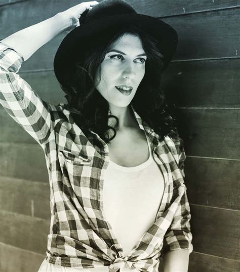 A Woman Wearing A Hat Leaning Against A Wall