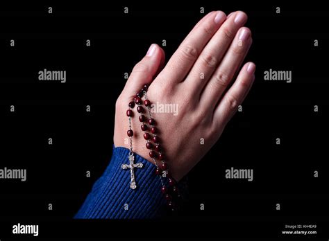 Female Hands Praying Holding A Rosary With Jesus Christ In The Cross Or