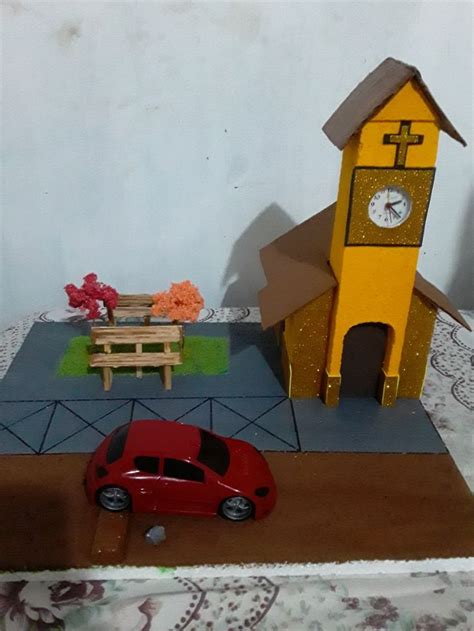A Toy Car Is Parked In Front Of A Small Yellow Clock Tower On A Table