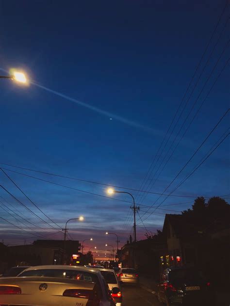 Cars Are Parked On The Side Of The Road At Night With Street Lights In