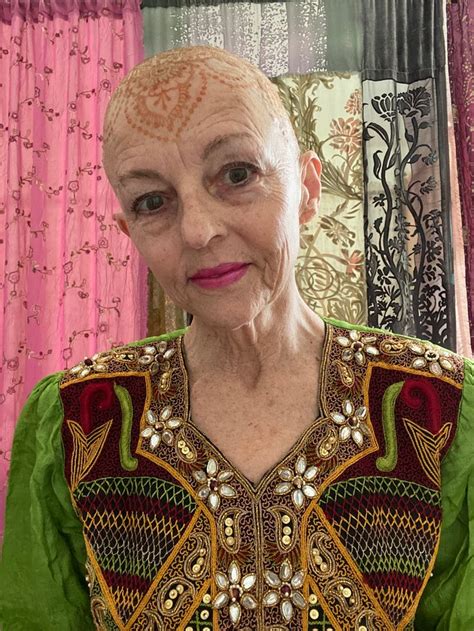 An Older Woman Wearing A Green Dress And Smiling At The Camera With Her Hair Shaved Back