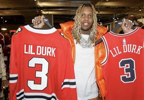 A Man Holding Up Two Red Jerseys In Front Of Other Men S Basketball