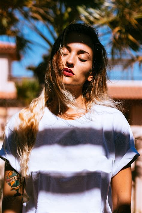 Portrait Of Woman With Eyes Closed Between Sun And Shadows By Stocksy