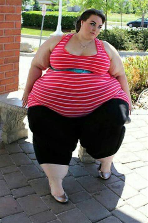 A Woman In Red And White Striped Shirt Standing On Brick Walkway With Her Hands Behind Her Back