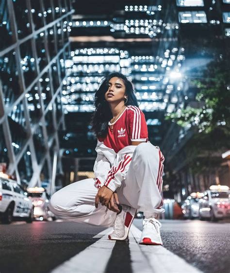 A Woman Squatting On The Ground In Front Of Some Cars And Buildings At