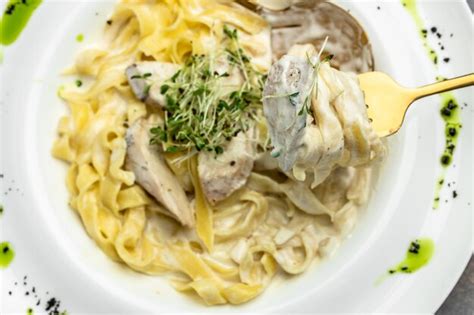 Fettuccine alfredo em molho cremoso frango parmesão no prato branco