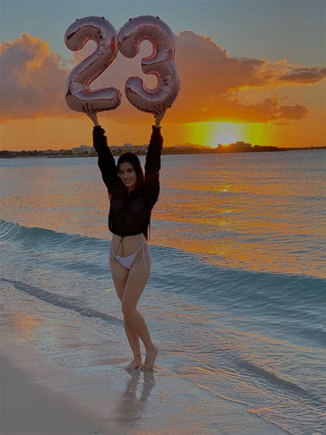 A Woman Is Standing On The Beach With Her Arms In The Air While Holding