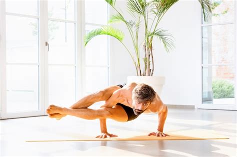 Hombre haciendo un astavakrasana o pose de ocho ángulos balanceándose